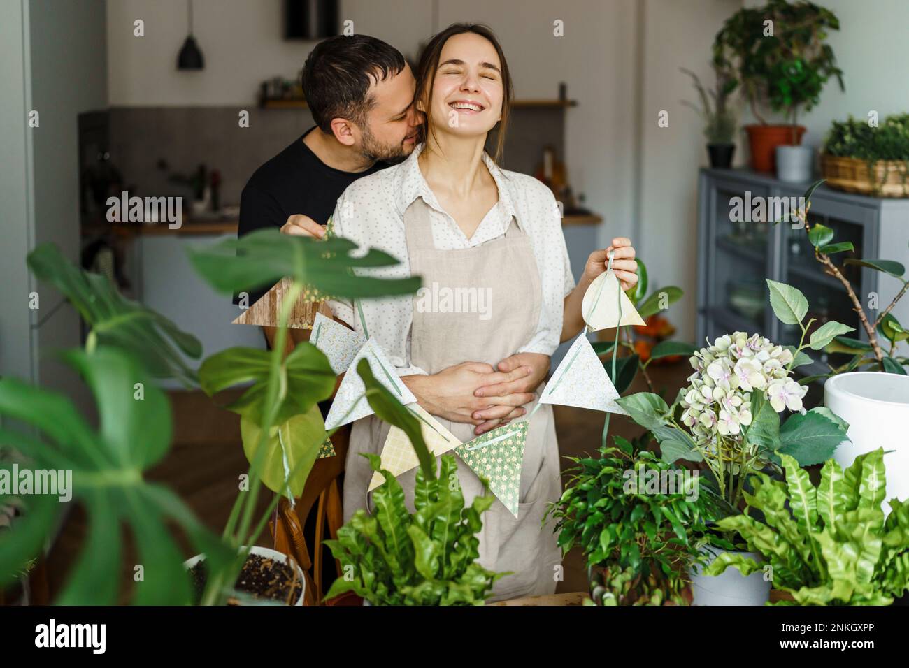 Man hugging woman from back by plants at home Stock Photo - Alamy