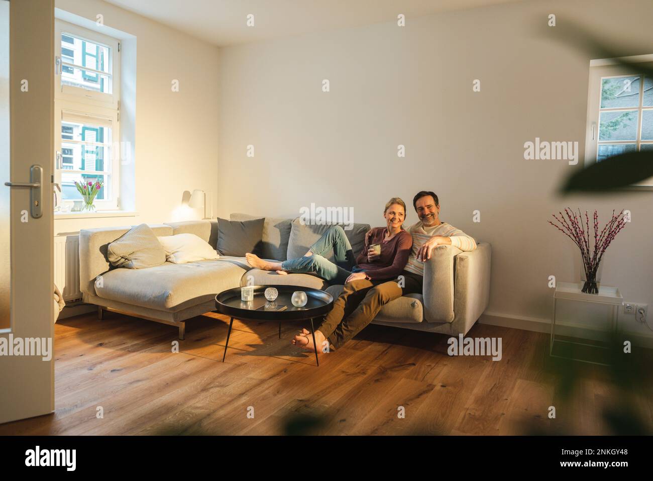 Husband and wife sitting on sofa in living room at home Stock Photo - Alamy