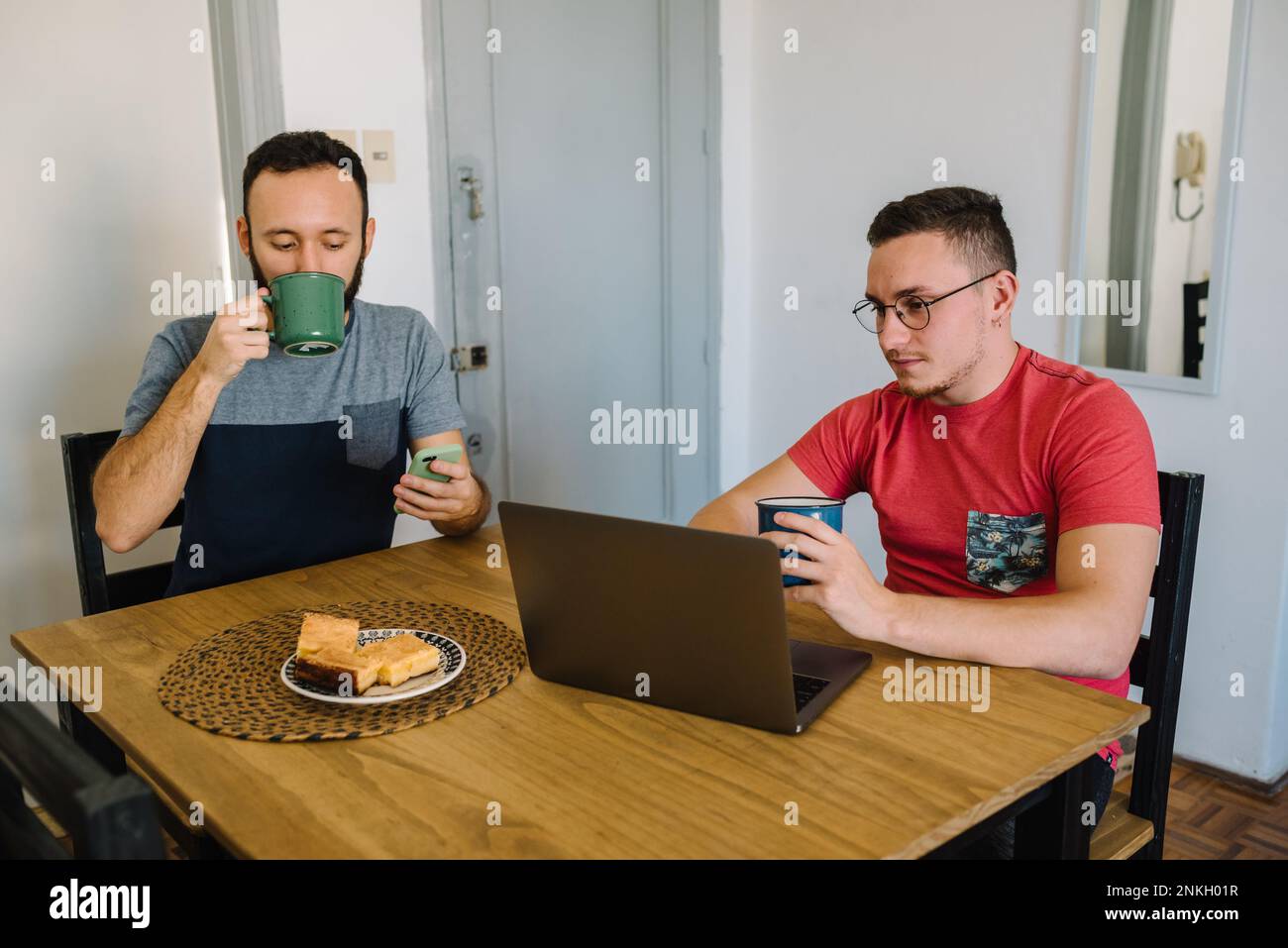 Two men sitting using laptop and phone Stock Photo - Alamy