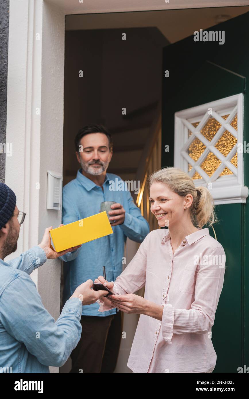 Delivery person giving package to customers at doorway Stock Photo - Alamy Delivery person giving package to customers at doorway Stock Photo - Alamy