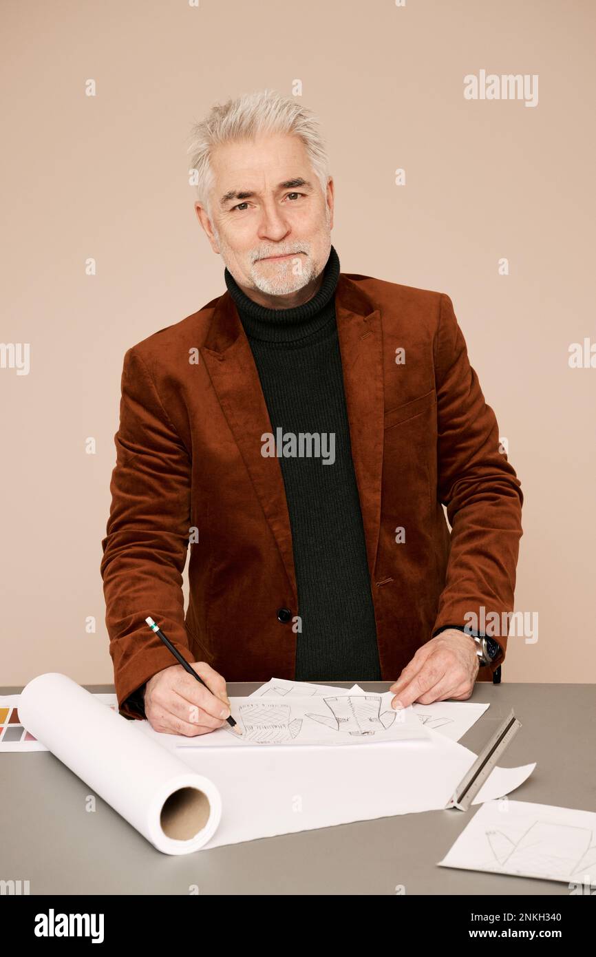 Smiling fashion designer sketching at desk in studio Stock Photo - Alamy