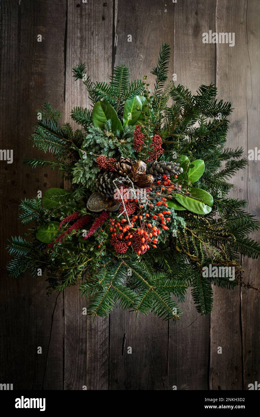 Autumnal arrangement of twigs, laurel, amaranthus, skimmia, rose hips ...