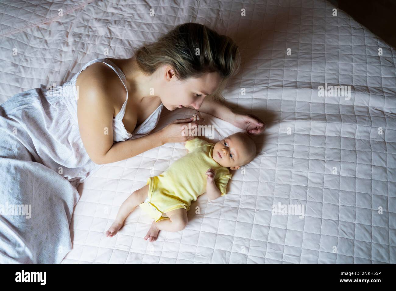 Mother spending leisure time with baby boy lying on bed Stock Photo - Alamy