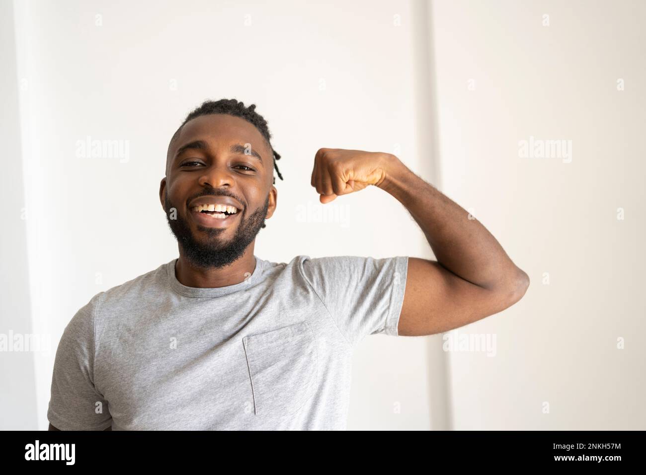 Man flexing muscles in front of wall Stock Photo - Alamy
