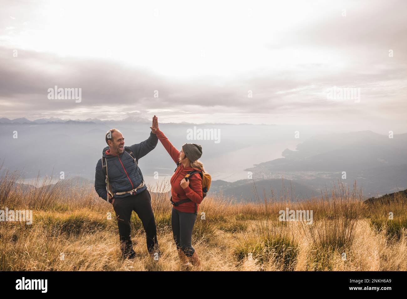 Cheerful man and woman giving high-five to each other standing on ...