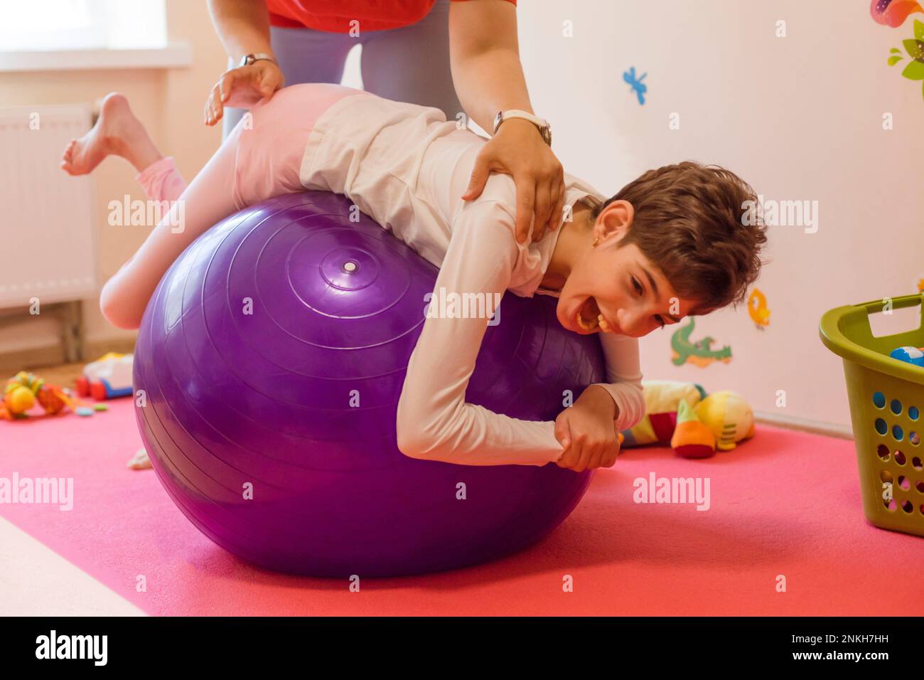 Physical therapist helping girl with disability in exercising on ...