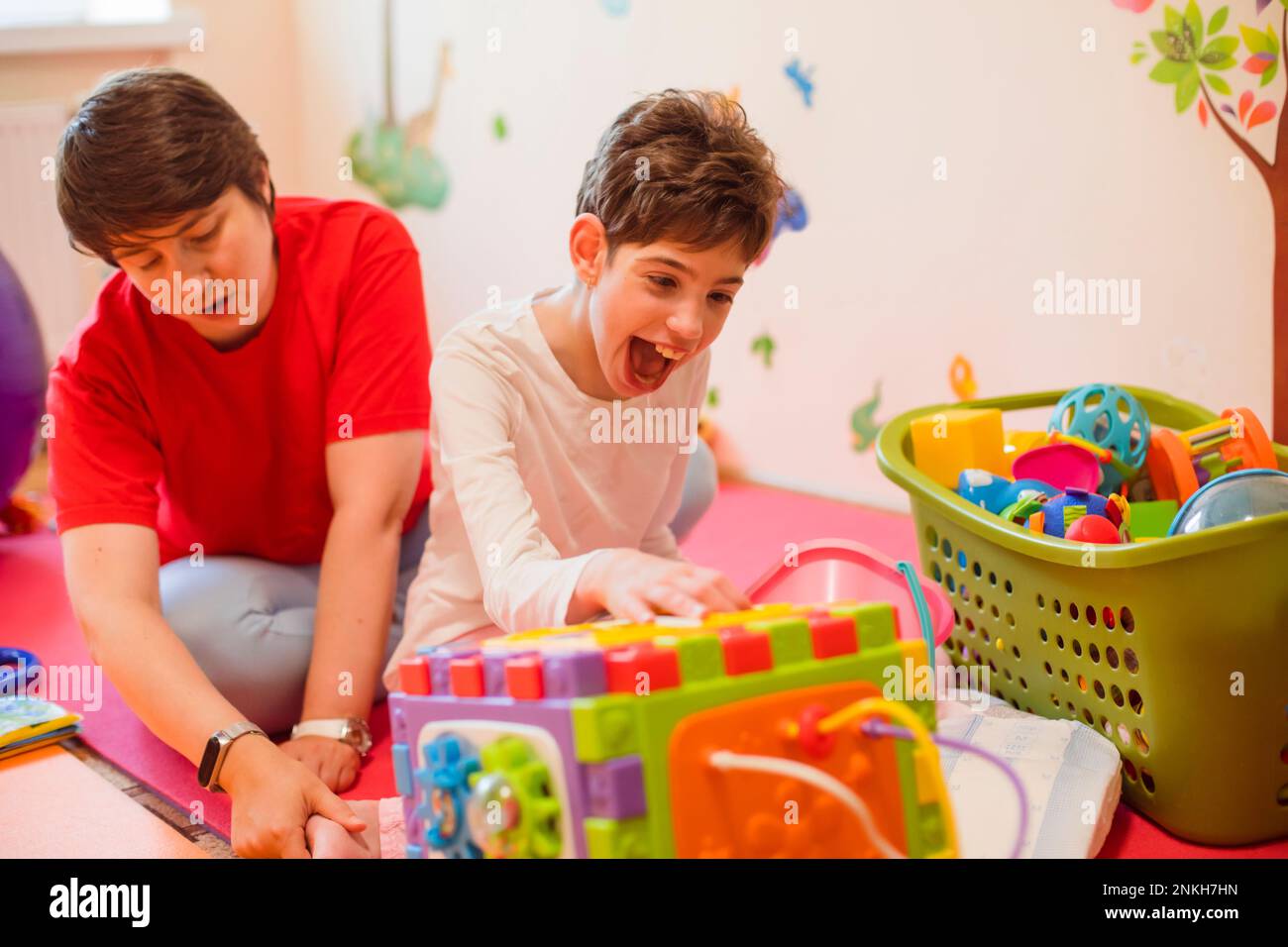 Happy physical therapist and girl with disability playing at ...