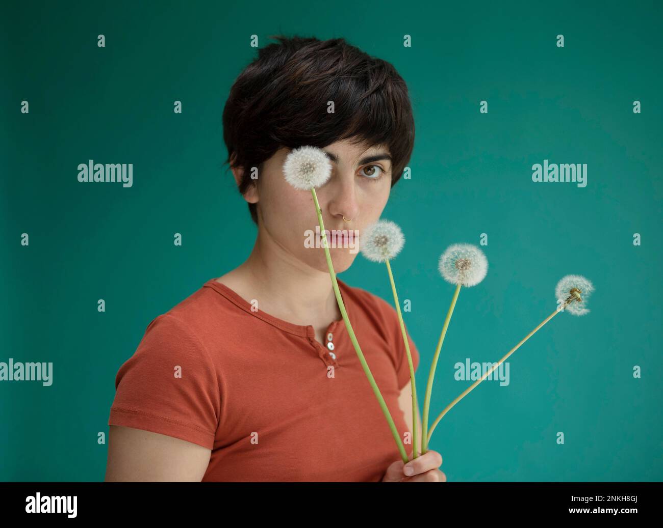 Woman covering eye with dandelion against green background Stock Photo ...