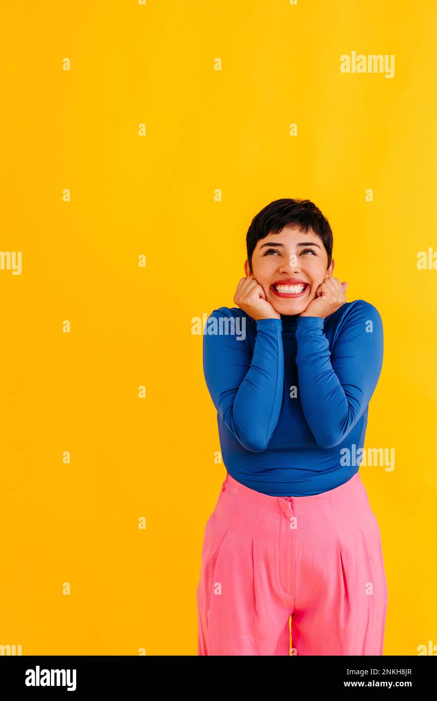 Excited woman with pixie cut against yellow background Stock Photo - Alamy