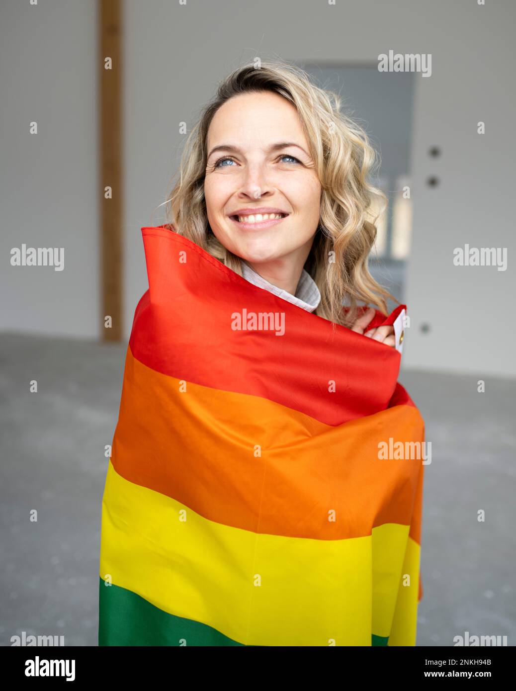 Happy woman wrapped in multi colored flag Stock Photo - Alamy