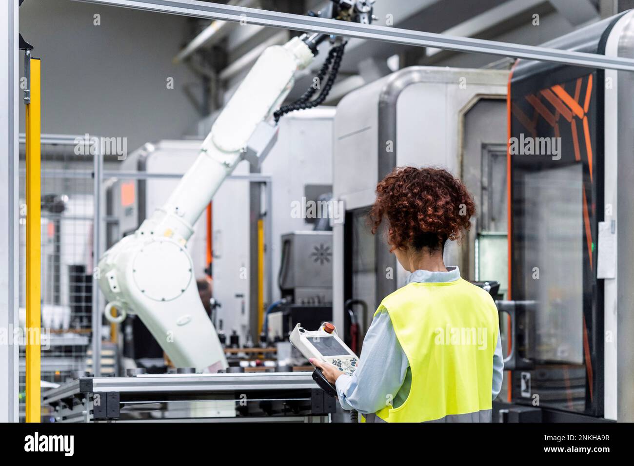 Engineer controlling robotic arm with equipment in factory Stock Photo - Alamy