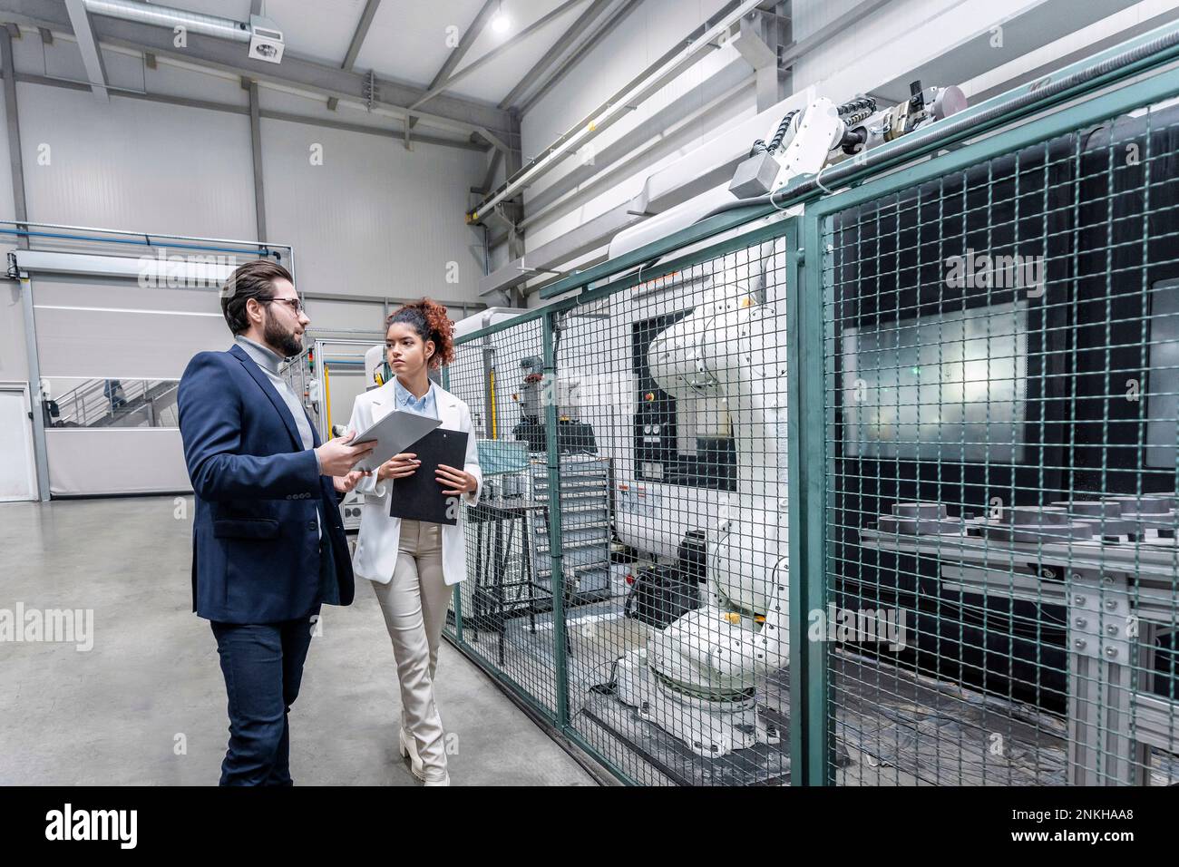 Young engineers discussing over robotics arm in industry Stock Photo ...