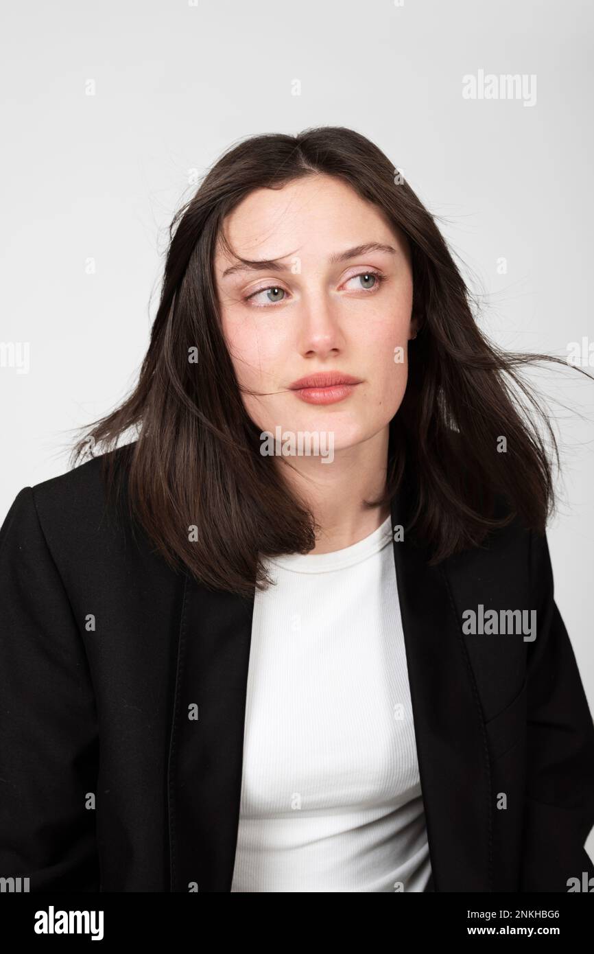 Thoughtful young woman wearing blazer against white background Stock ...