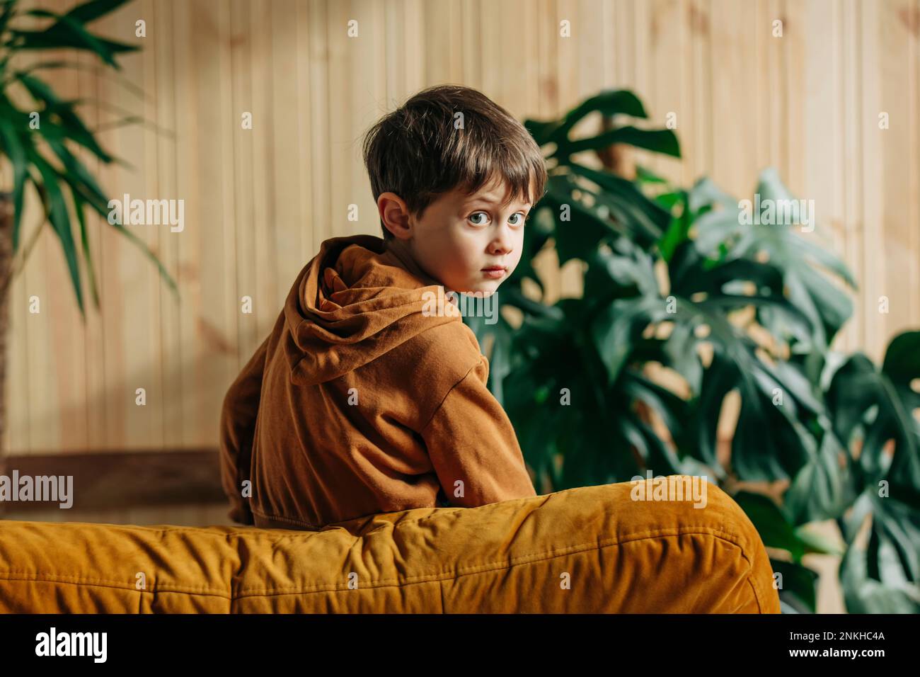 Cute boy sitting on sofa at home Stock Photo - Alamy