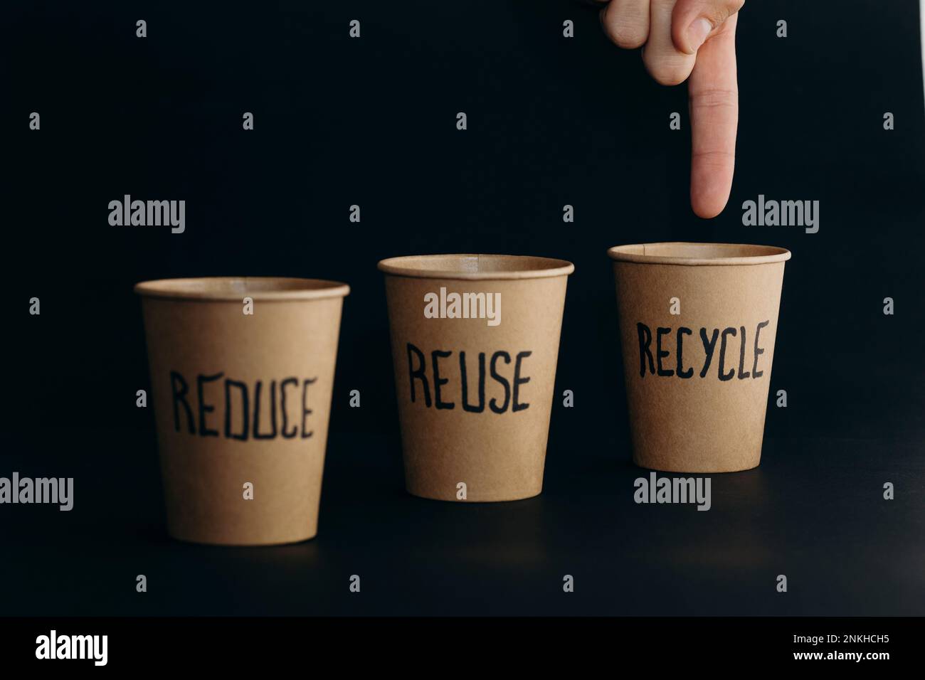 Man's hand pointing at reusable cup with recycle text written on it ...