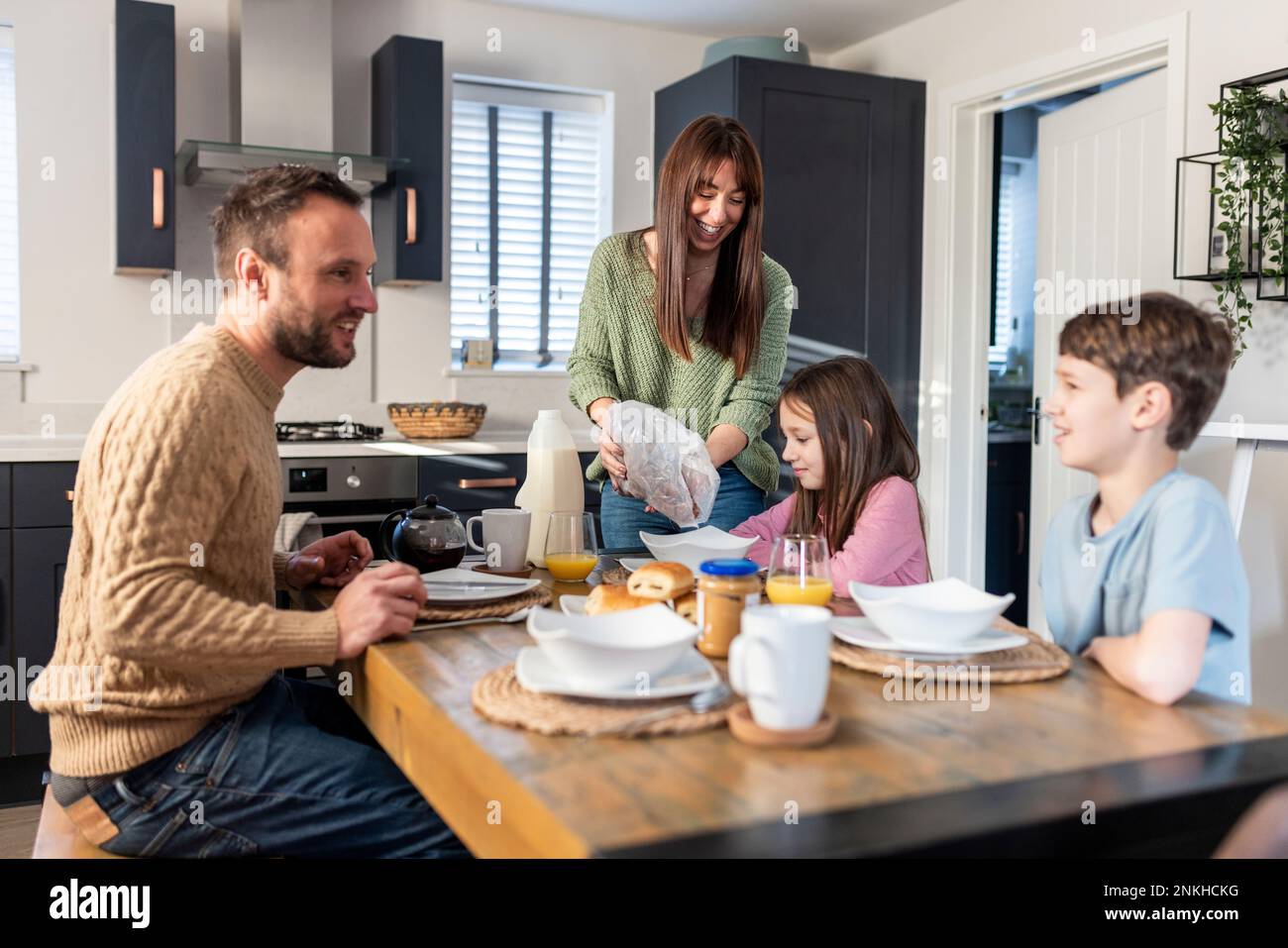 Happy family having breakfast together at table in kitchen Stock Photo ...