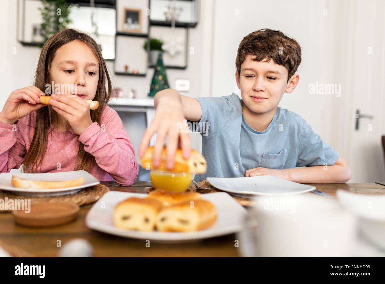 Brother and sister having breakfast at table Stock Photo - Alamy