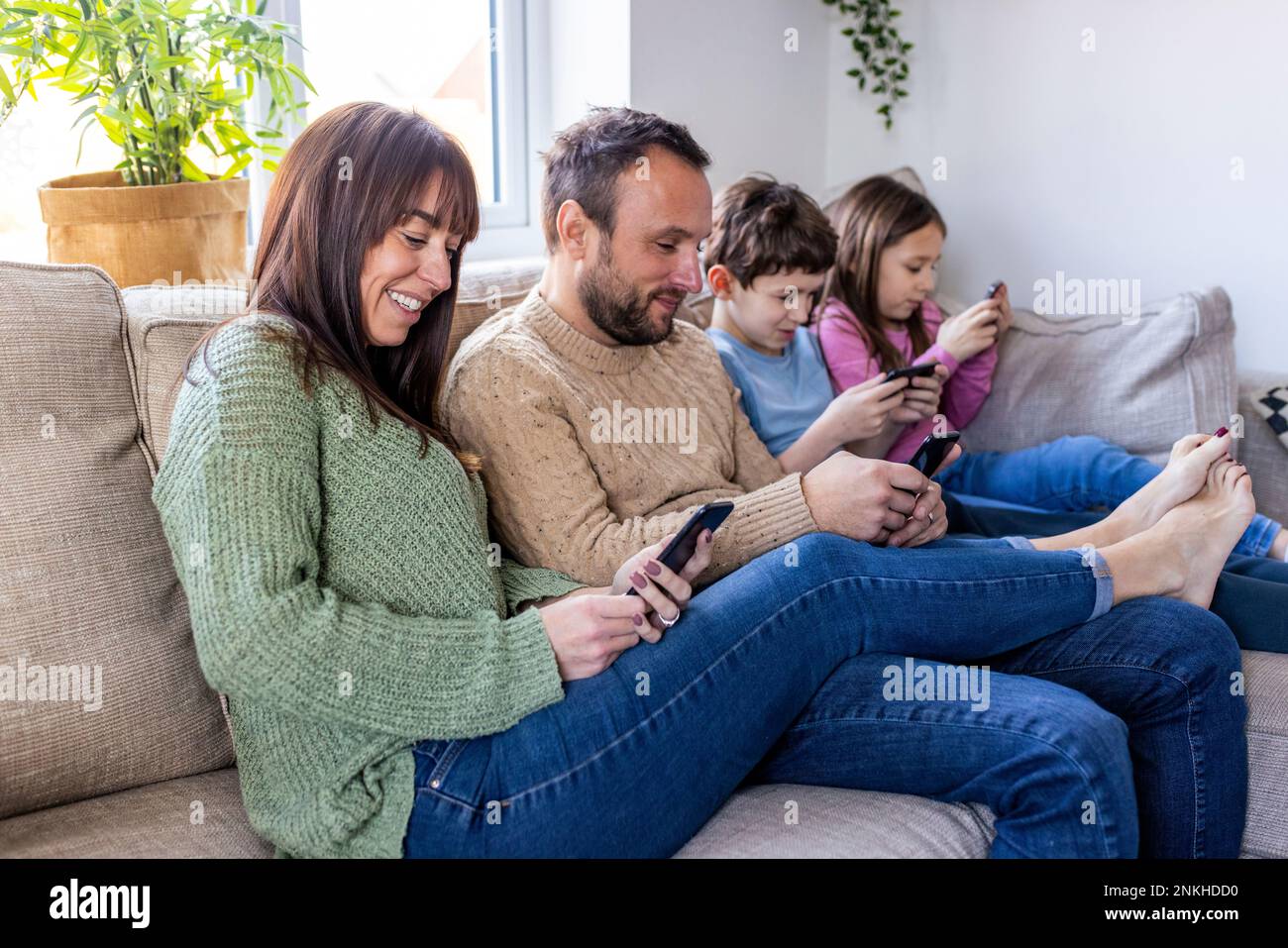 Happy man and woman with children using smart phone at home Stock Photo ...
