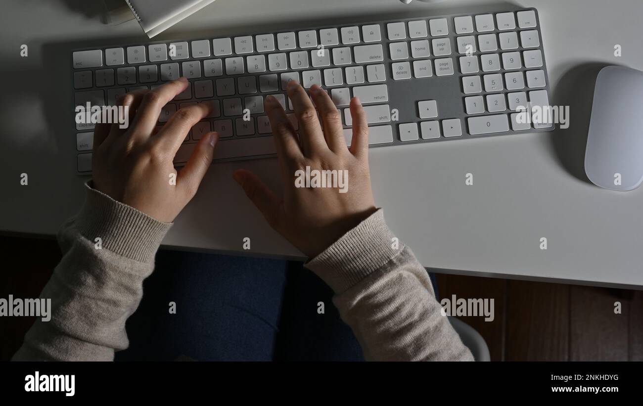 Top view of a female office worker working at her computer desk, typing ...