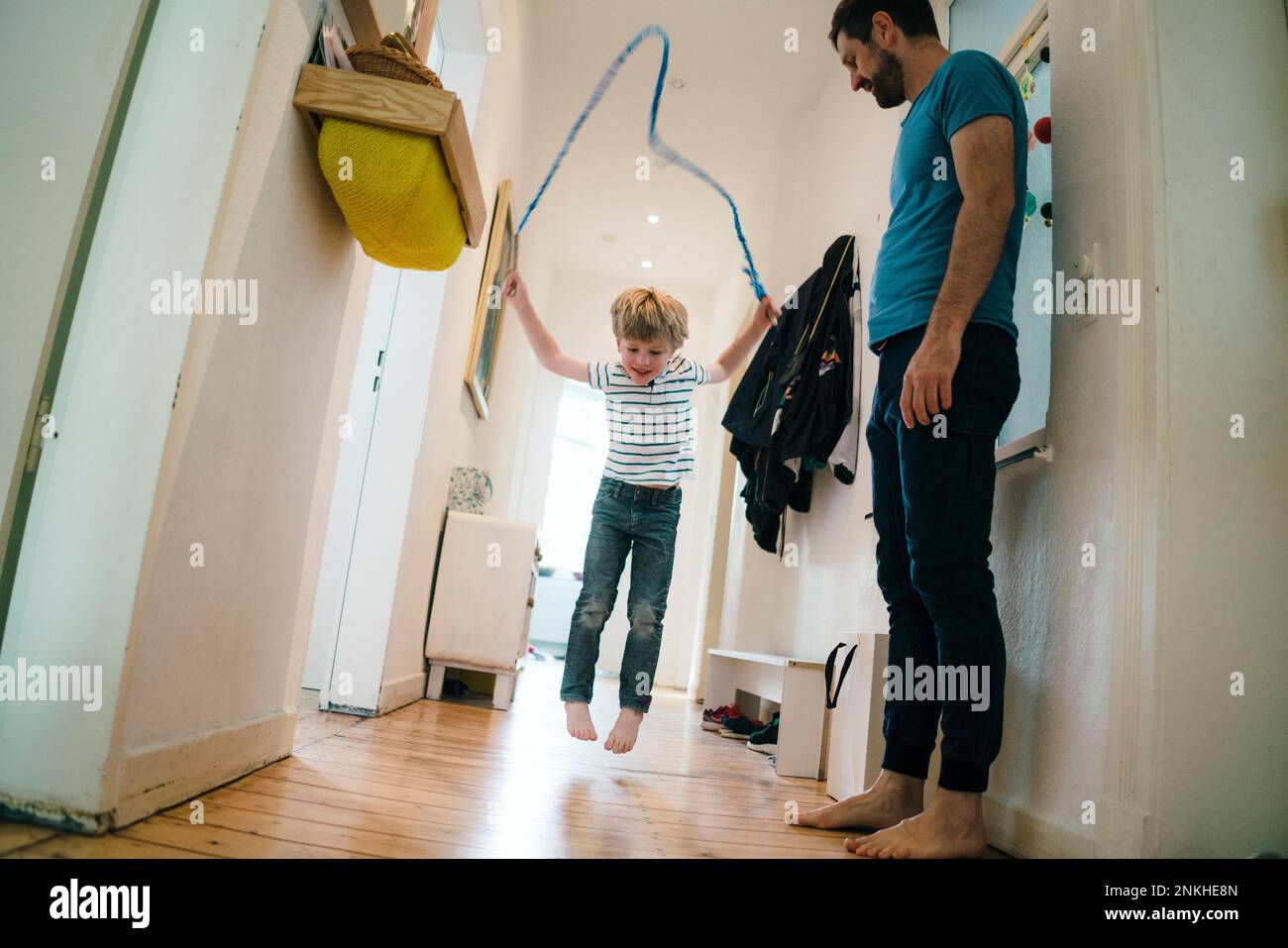 Playful boy jumping over skipping rope at home Stock Photo - Alamy