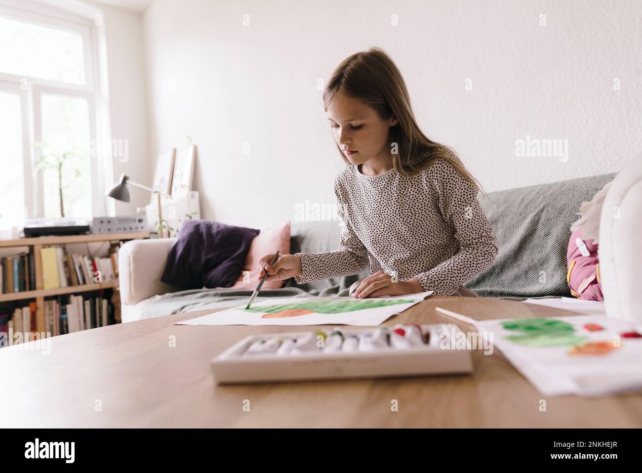 Girl doing painting with paintbrush on paper at home Stock Photo - Alamy