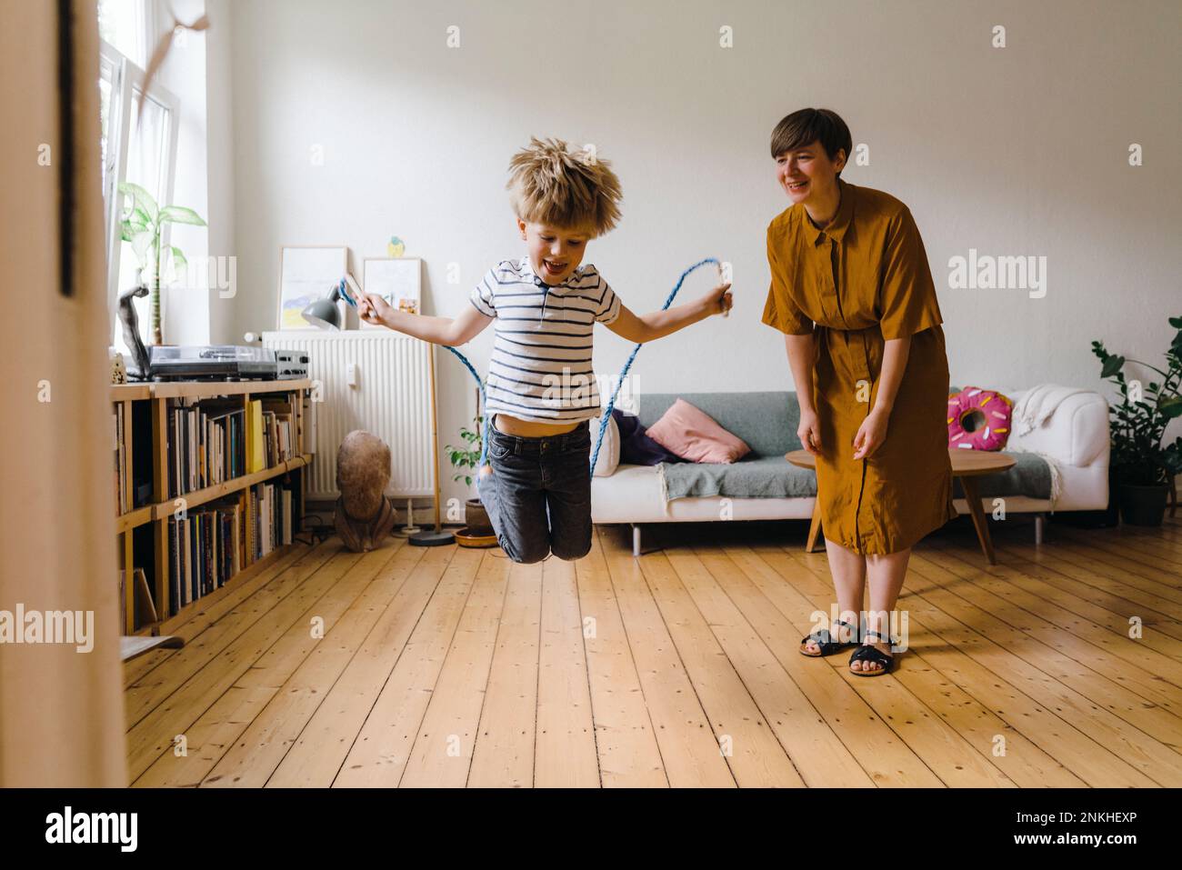 Mother cheering son playing with jump rope in living room at home Stock ...