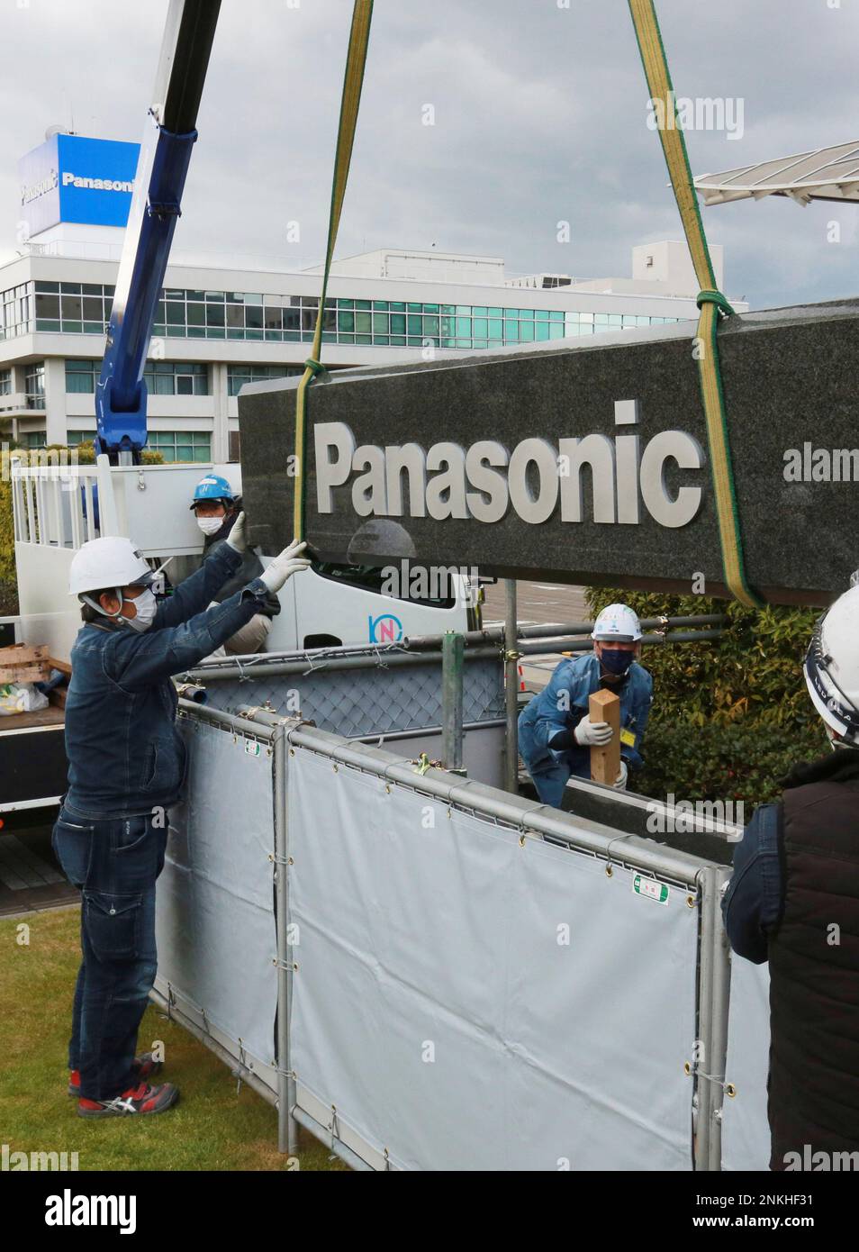 Workers prepare a new Panasonic logo board in Kadoma, Osaka Prefecture ...
