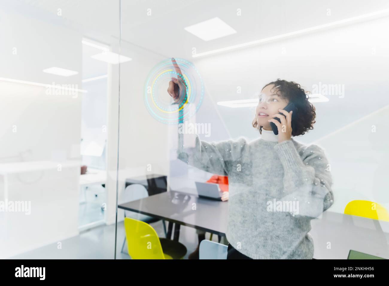 Businesswoman talking on smart phone and using projection glass screen ...