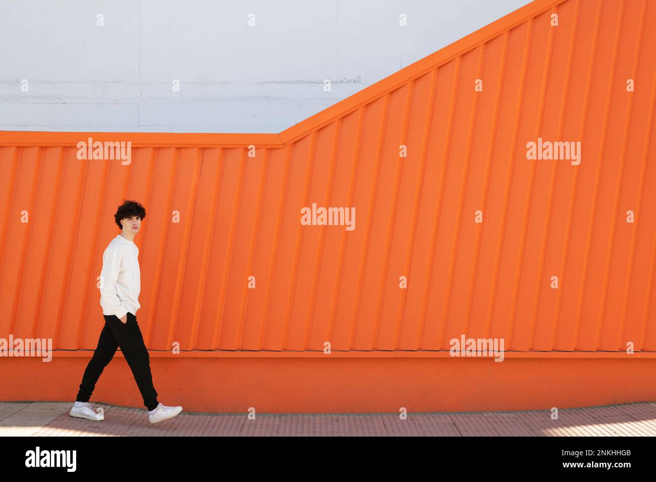 Man walking on footpath by wall Stock Photo - Alamy