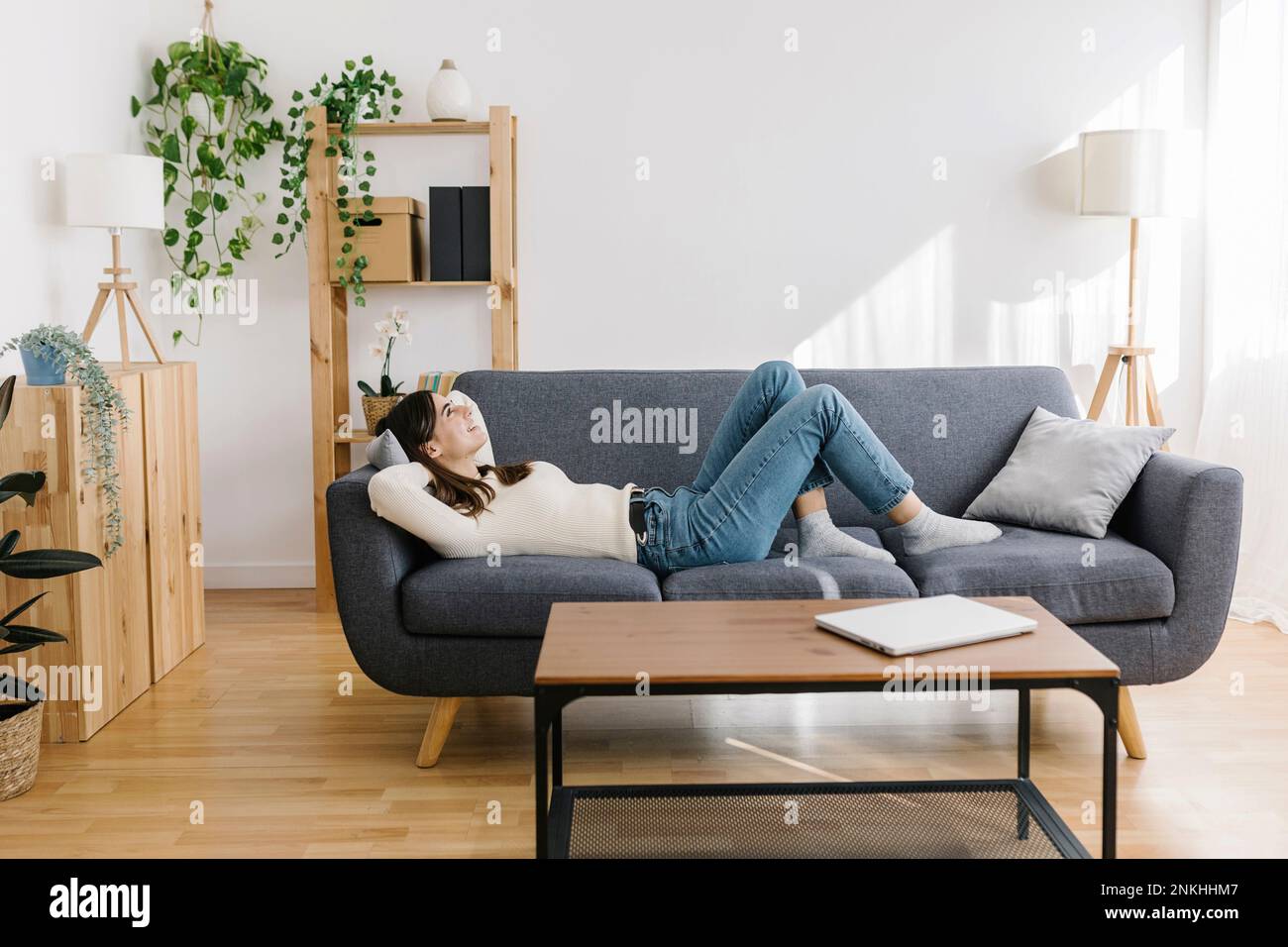 Woman lying down on sofa in living room Stock Photo - Alamy