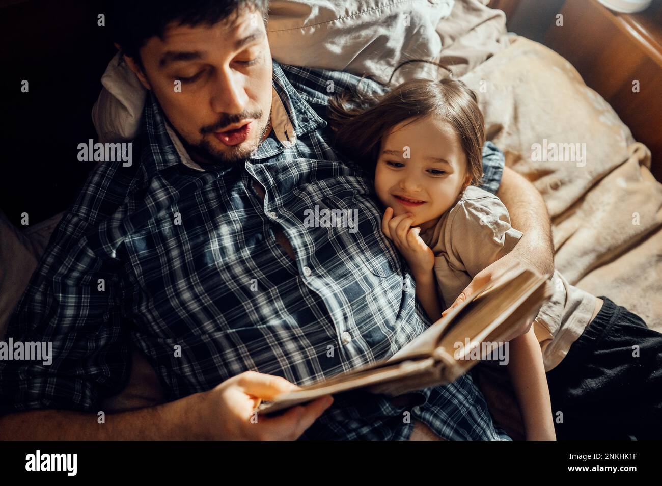 Father reading story book lying with son on bed Stock Photo - Alamy