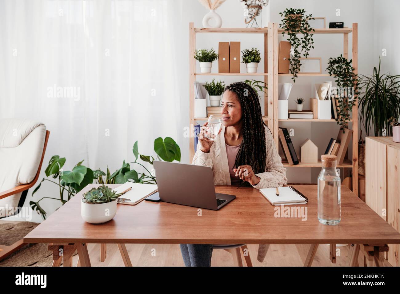 Freelancer holding glass of water sitting at desk Stock Photo - Alamy