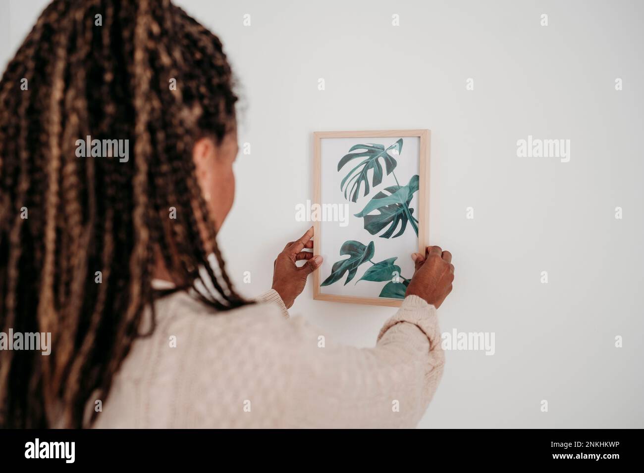 Mature woman hanging picture frame on wall at home Stock Photo - Alamy