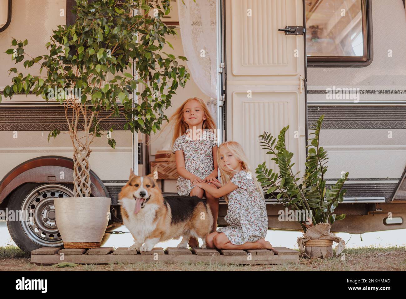 Sisters sitting with corgi dog at doorway of camper van Stock Photo - Alamy