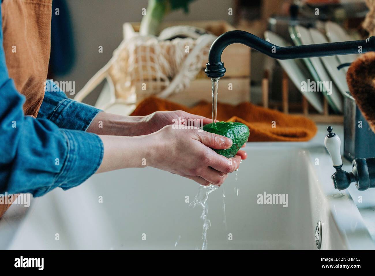 Hands of woman washing avocado in kitchen sink Stock Photo - Alamy