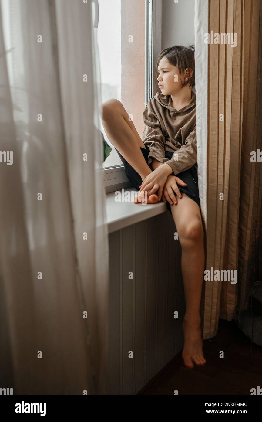 Pensive child on window sill hi-res stock photography and images - Alamy