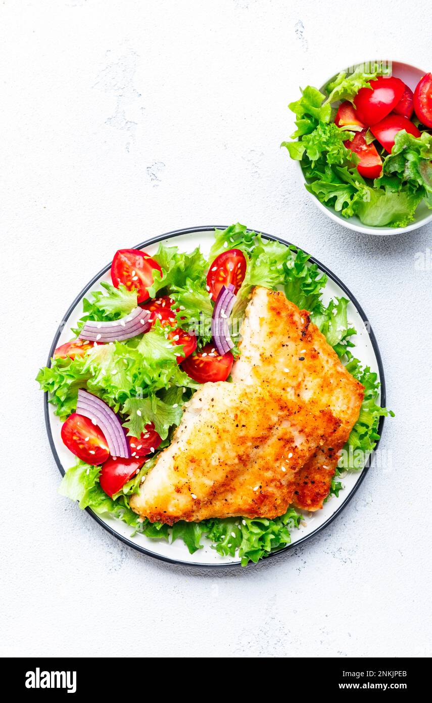 Fried cod fish with salad garnish from lettuce, cherry tomatoes and red ...