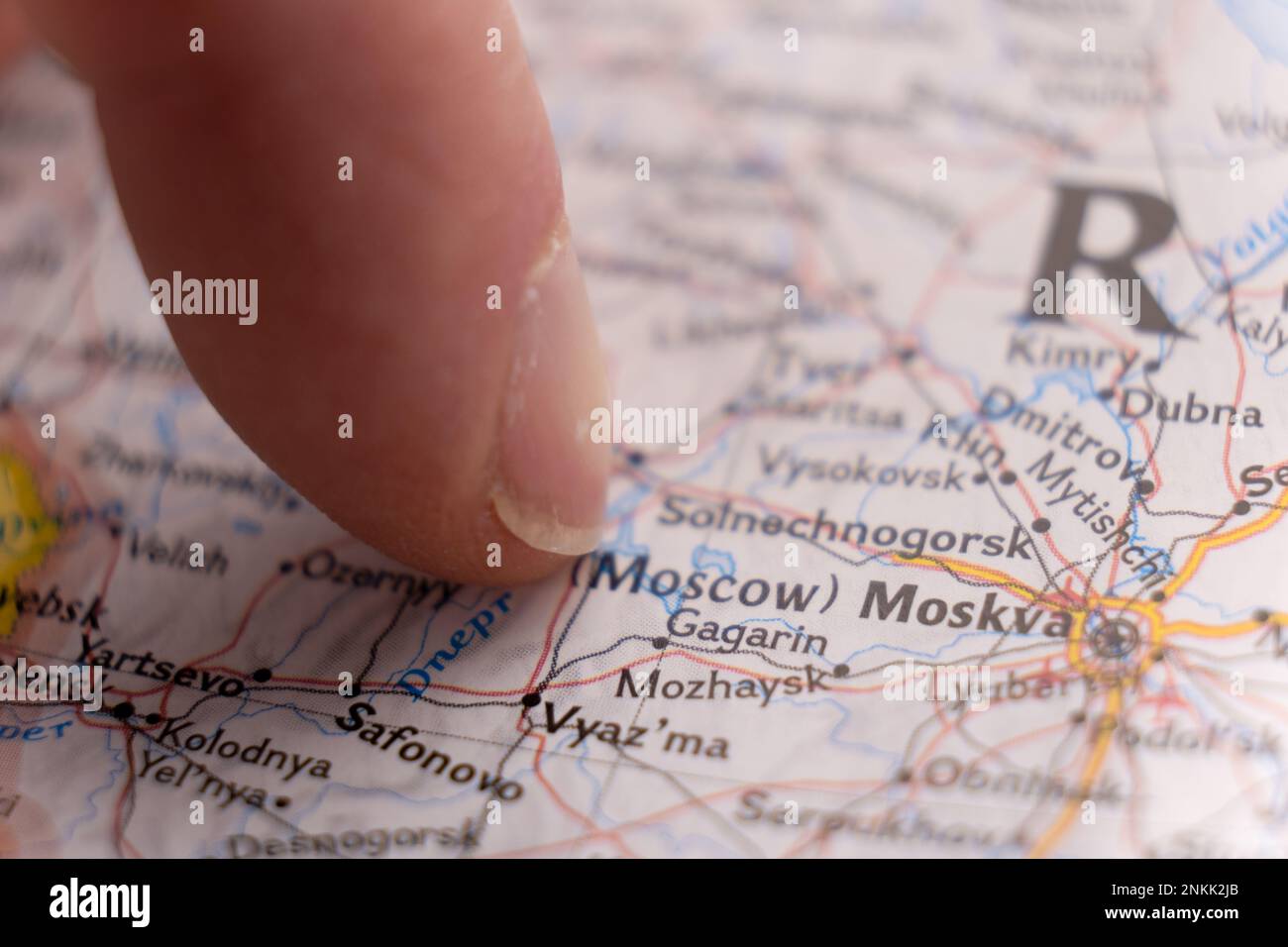 Close up of finger pointing to Moscow, Russia on detailed colorful map ...