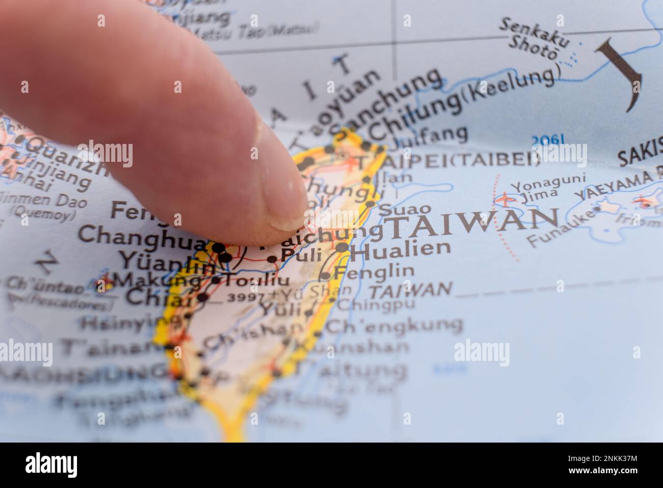 Finger pointing to Taiwan on detailed colorful map with selective focus ...