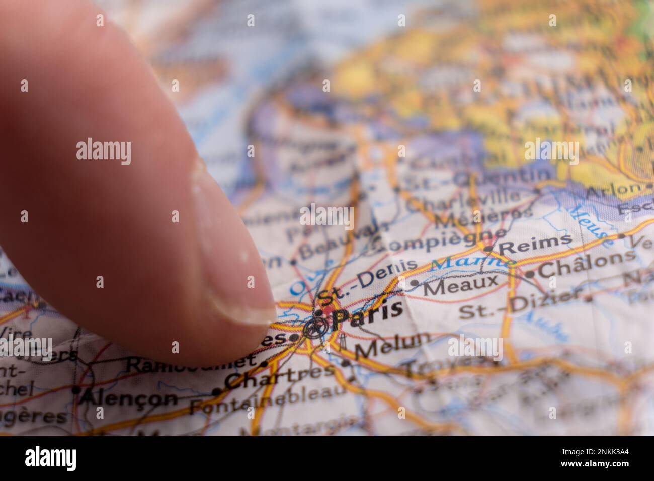 Finger pointing to Paris, France on detailed colorful map with ...