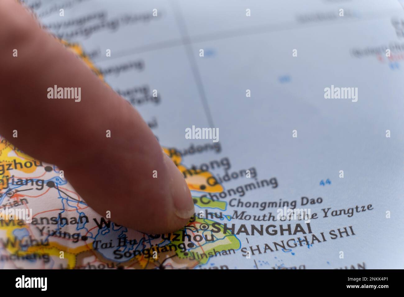 Finger pointing to Shanghai, China on detailed colorful map with ...