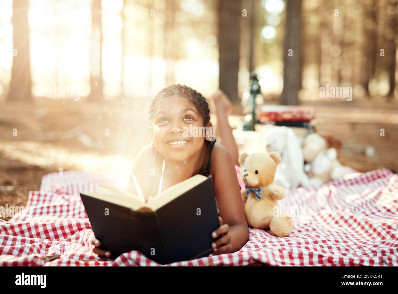 Reading is dreaming with open eyes. a little girl reading a book with ...