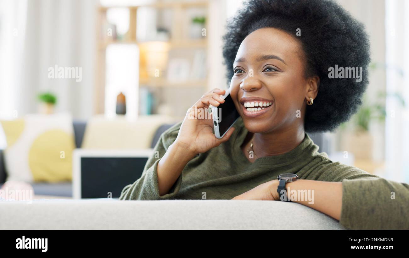Happy African woman talking on the phone while relaxing on her cozy ...