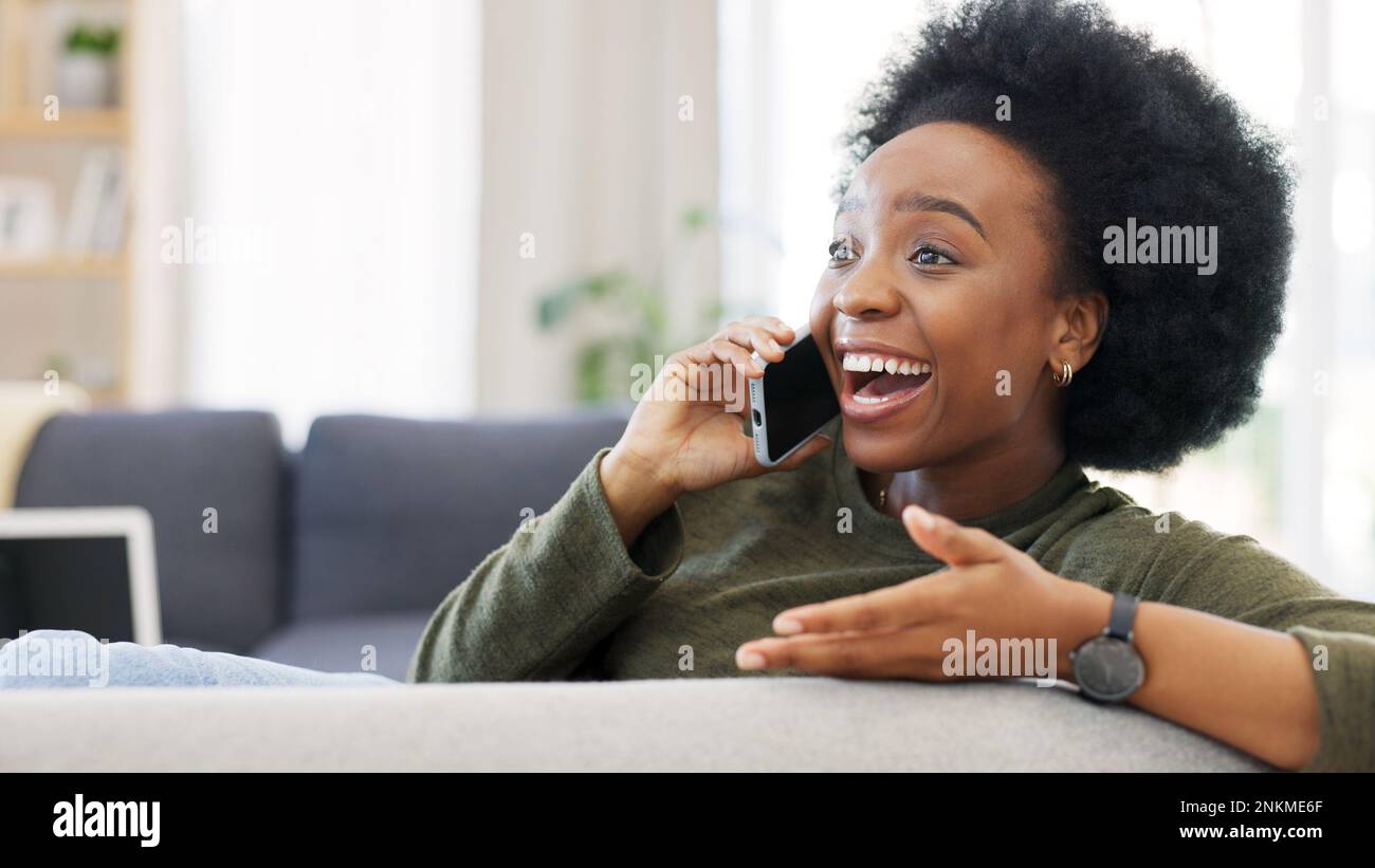 Happy African woman talking on the phone while relaxing on her cozy ...