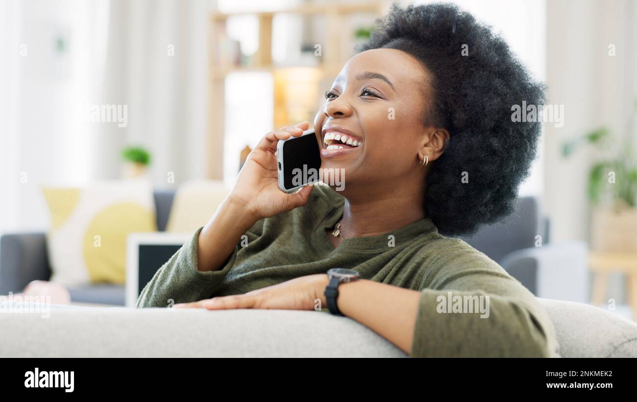 Happy African woman talking on the phone while relaxing on her cozy ...