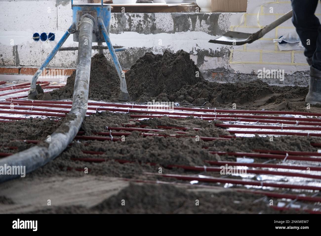 Semi-dry floor screed - a worker shovels a construction mixture through ...