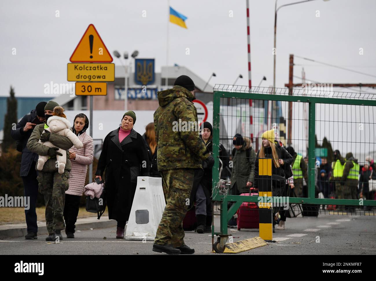 A Polish border guard stands at a gate as people, fleeing Ukraine ...
