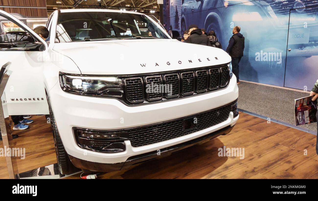 Crowds looking at new car models at Auto show. Wagoneer truck on ...