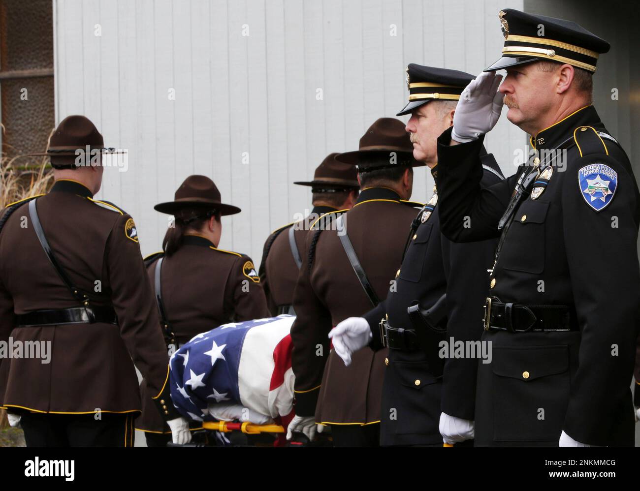 Honor guard members salute as a procession of law enforcement officers ...