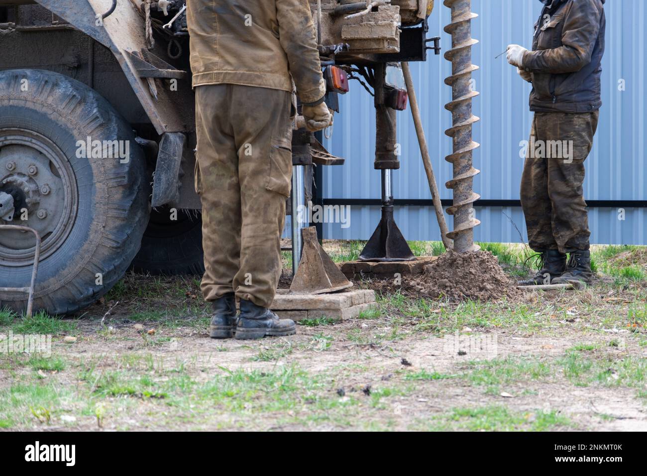 Team of workers with drilling rig on car are drilling artesian well for ...